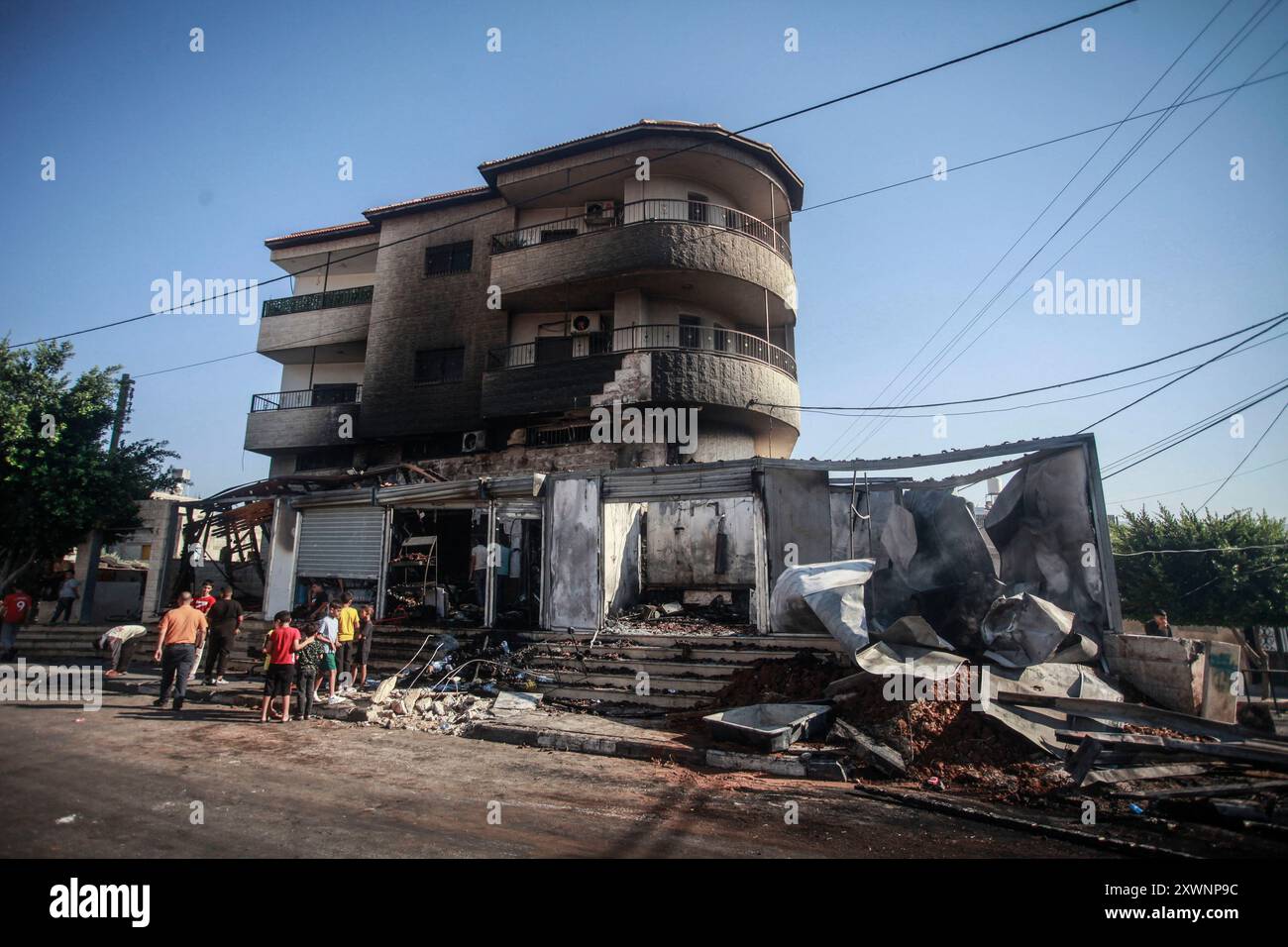 Palestinians gather around a destroyed and burned house by Israeli ...