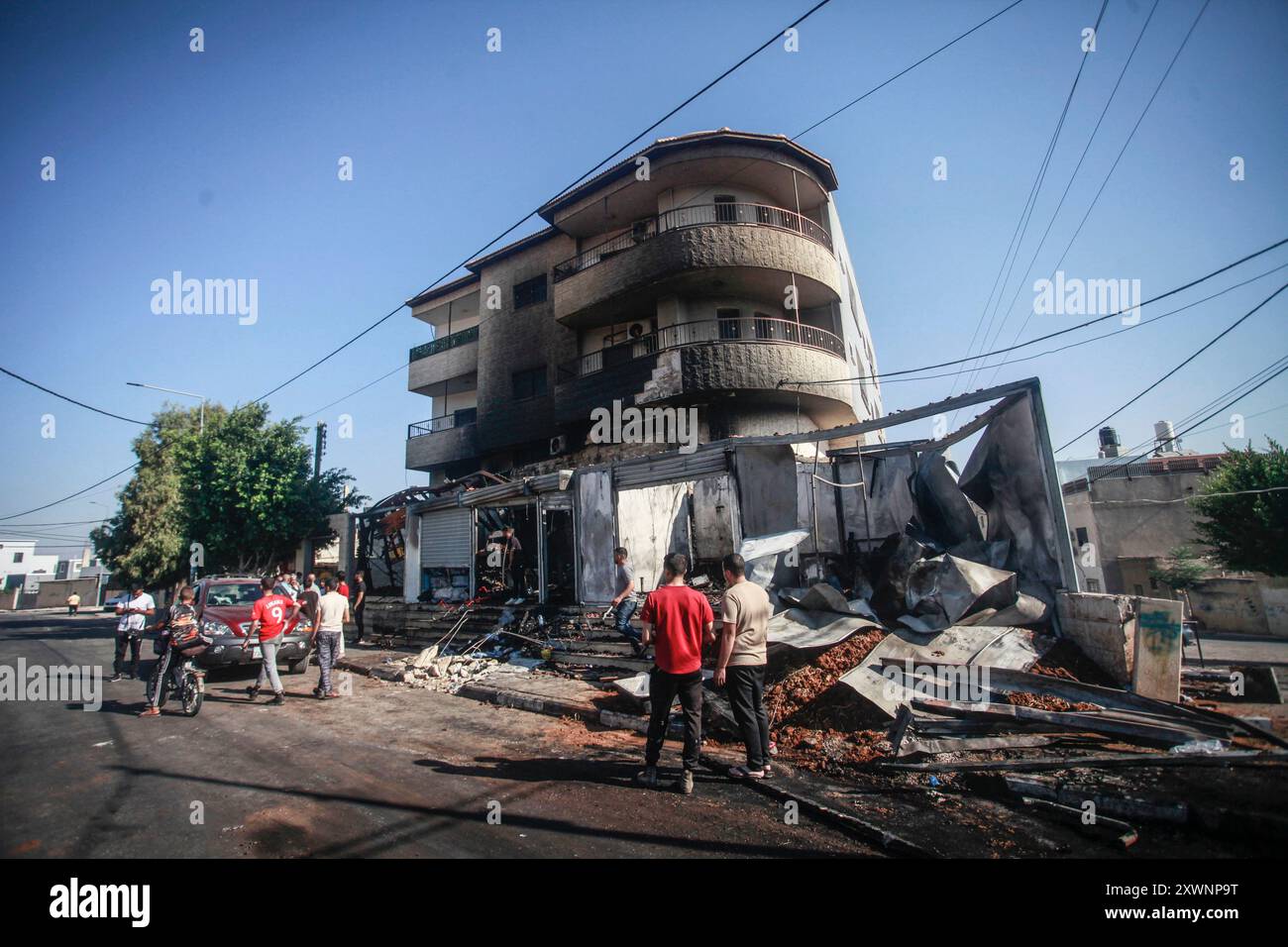 Palestinians gather around a damaged and burned house by Israeli forces ...