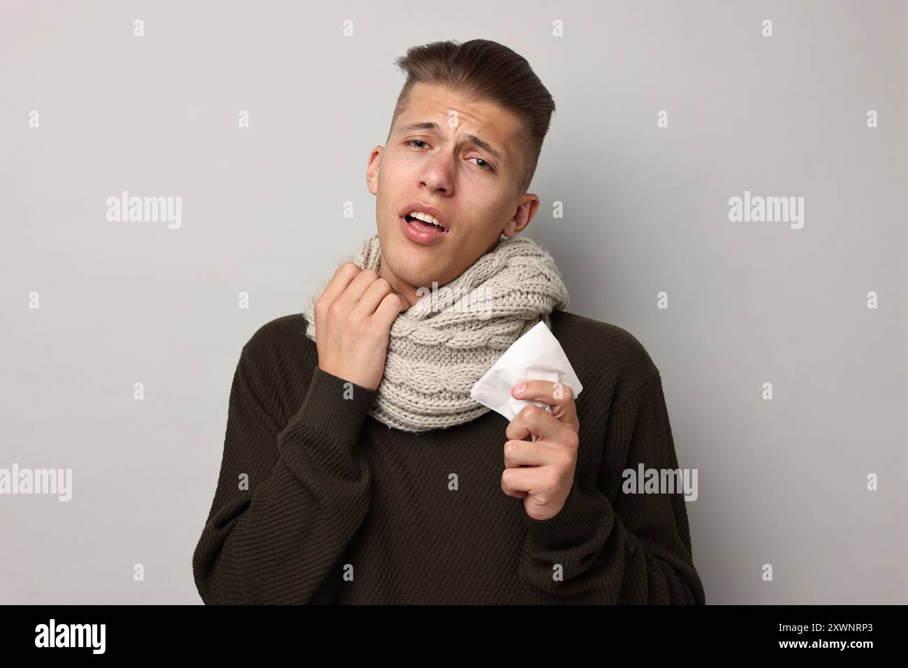 Sick man with tissue suffering from cold symptoms on light grey ...