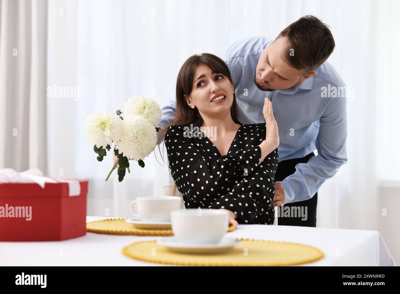 Bad date. Embarrassed woman refusing from man's kiss indoors Stock ...