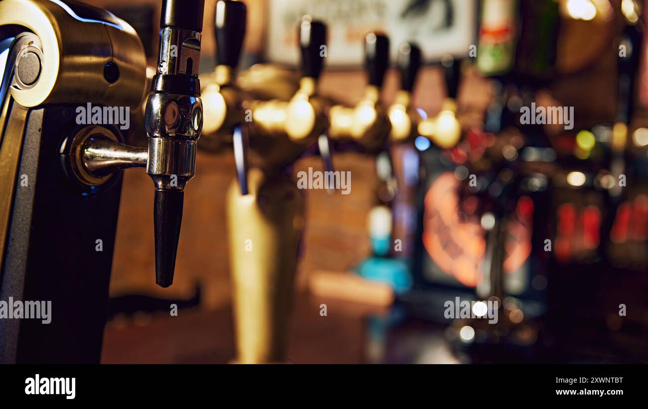 Close-up of row of shiny beer taps with handles, set against dark ...