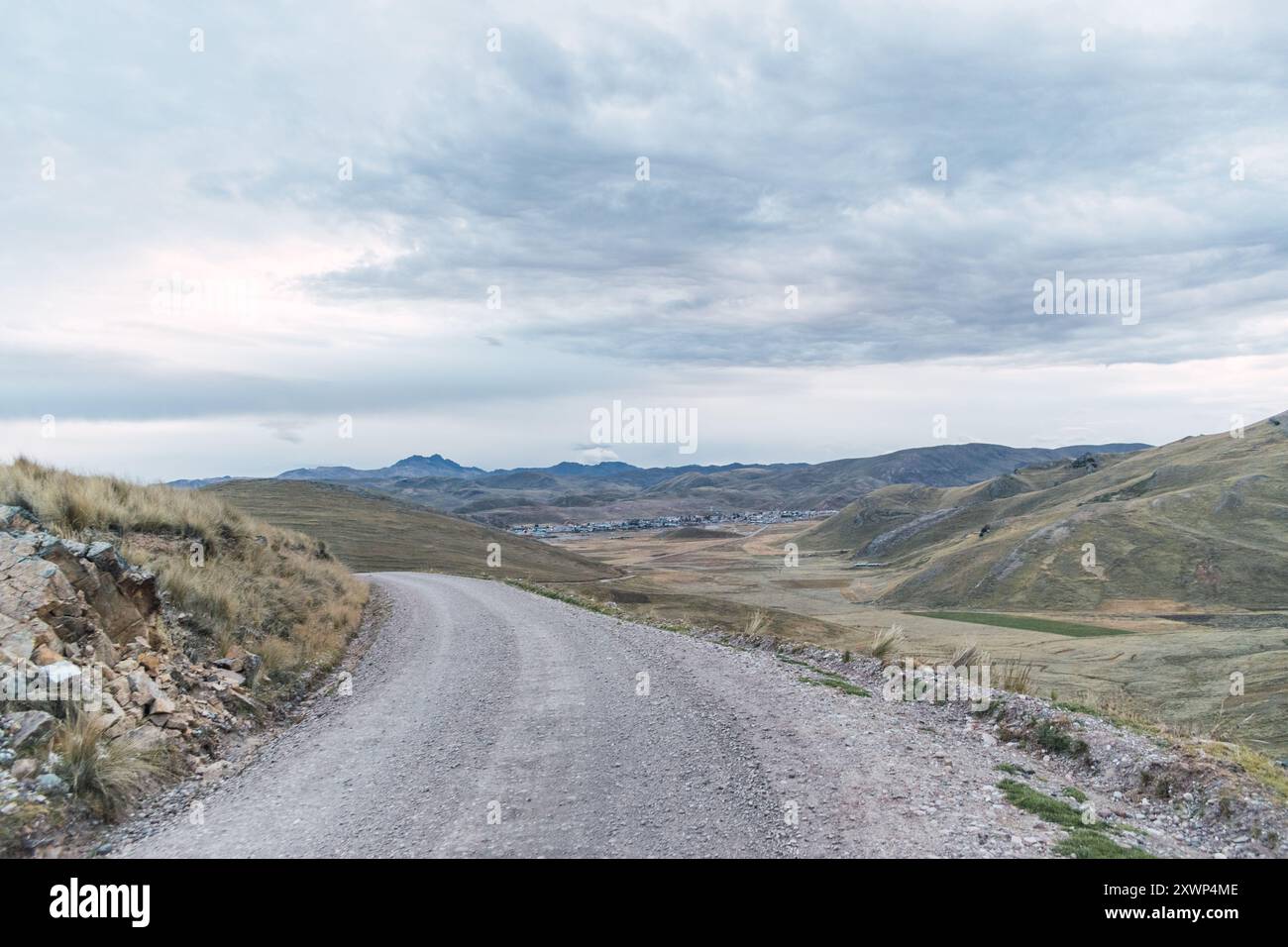 dirt road in the Andes of Peru with a blue sky and gray clouds at ...