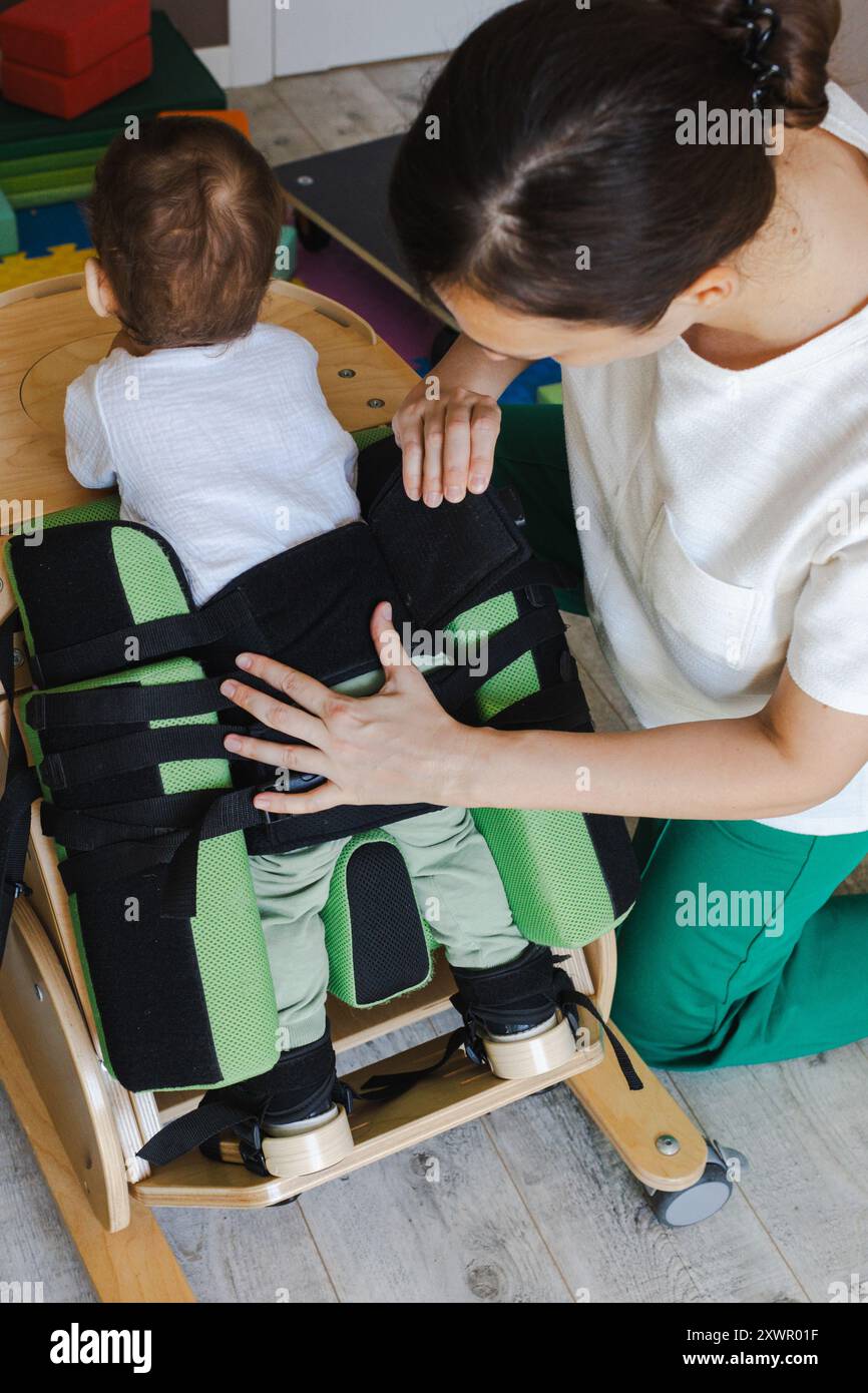 Female rehabilitator putting a 1-year-old male child with movement ...