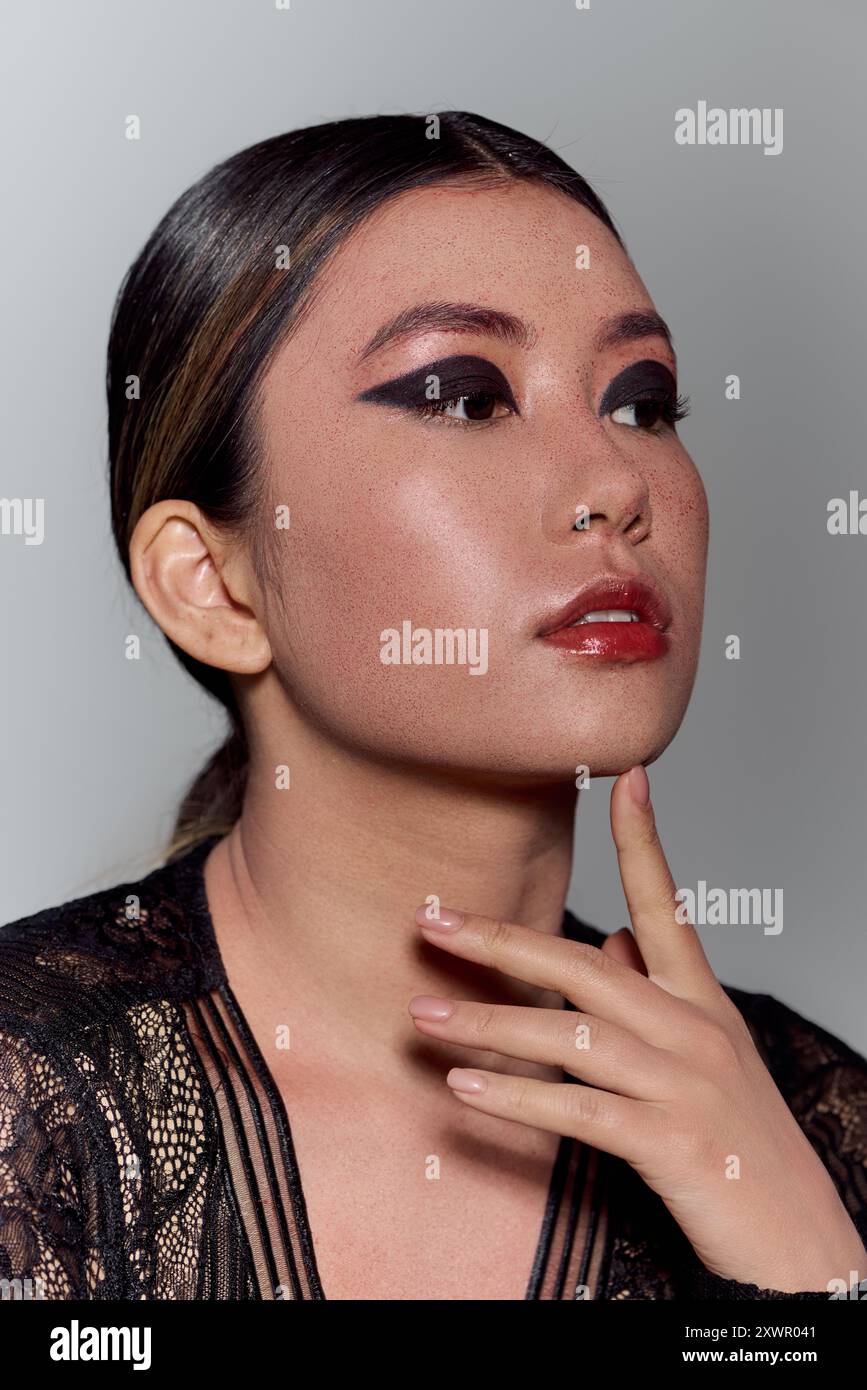 A young Asian woman with dark eyeliner and glossy lips poses for a ...