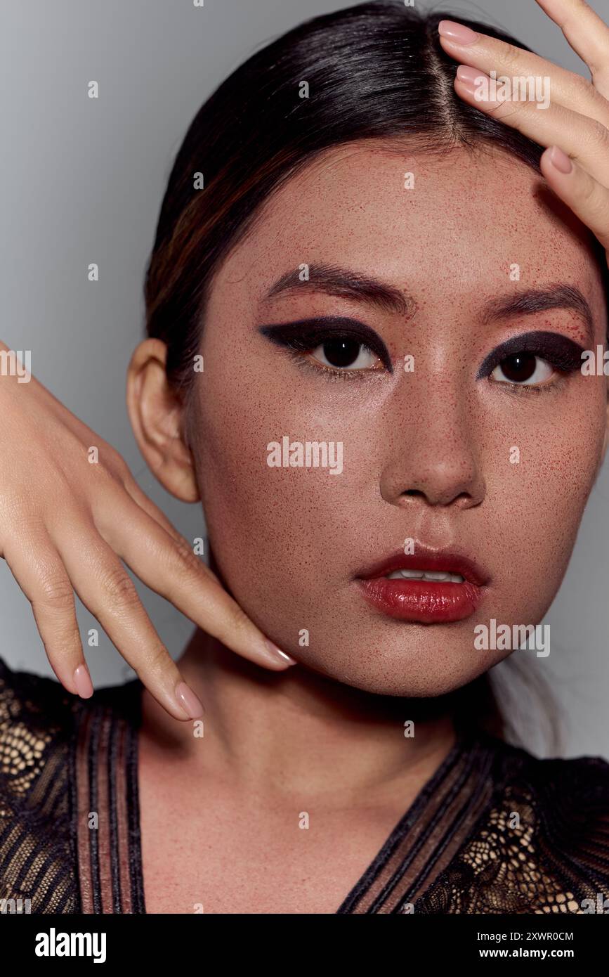 A beautiful Asian woman poses with dramatic makeup and a hint of lace ...