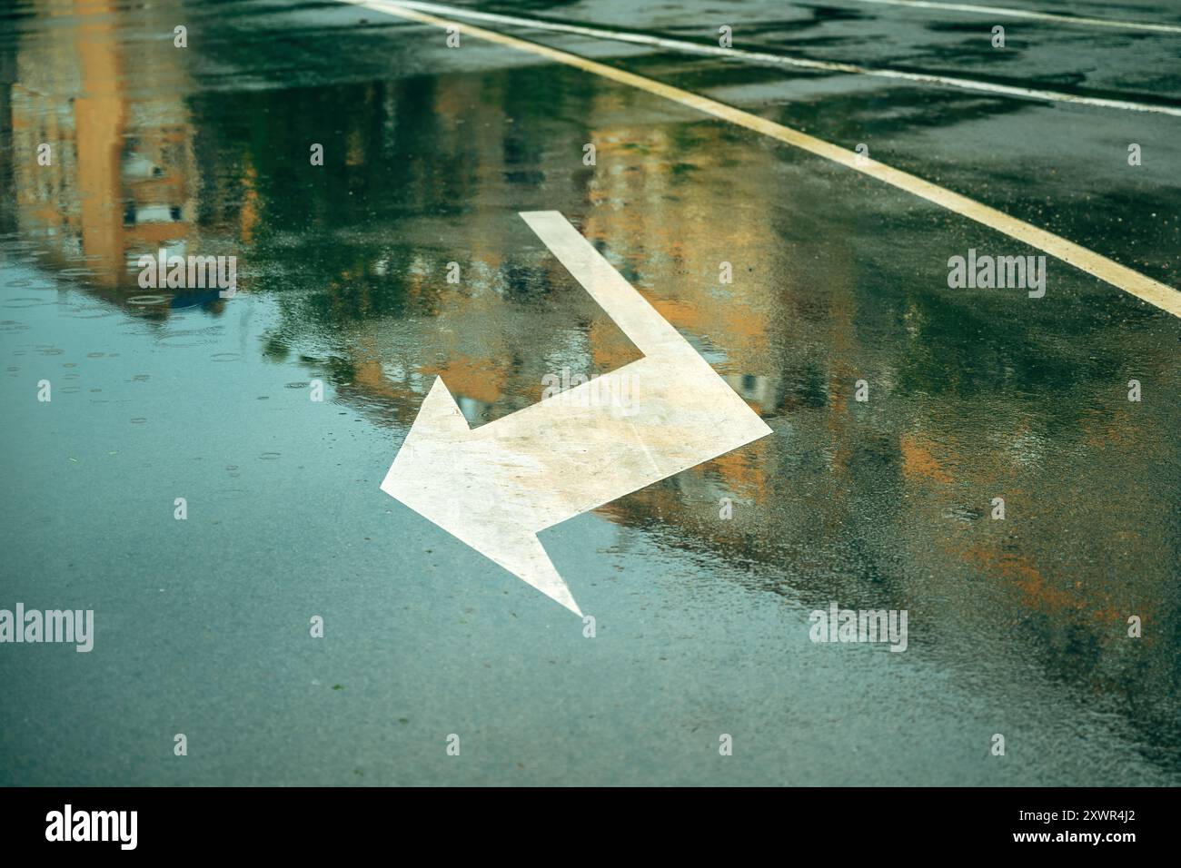 Turning arrow symbol on asphalt road on a rainy day, selective focus ...