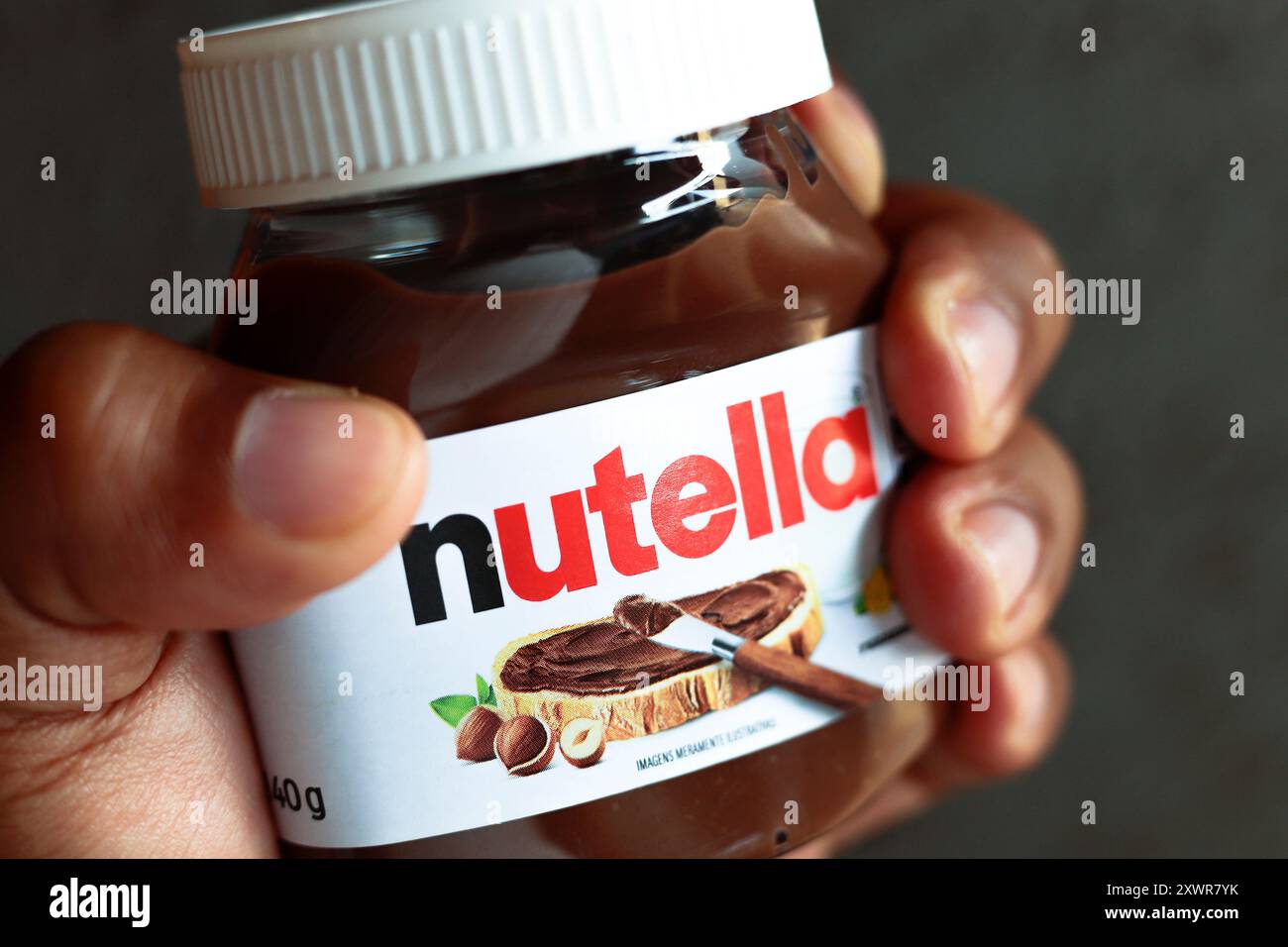 in this photo illustration, a hand seen holding a bottle with Nutella ...