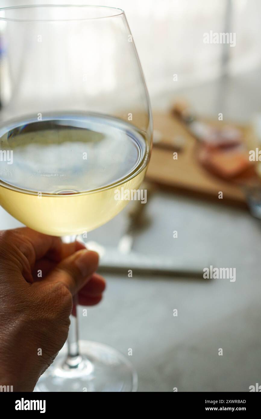 A woman enjoying an aperitif with a glass of cold white wine in her ...