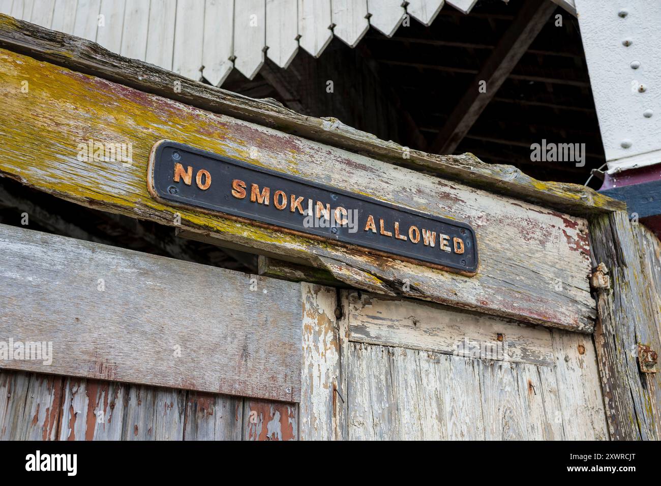 A weathered 'No Smoking Allowed' sign on a rustic, decaying wooden door ...