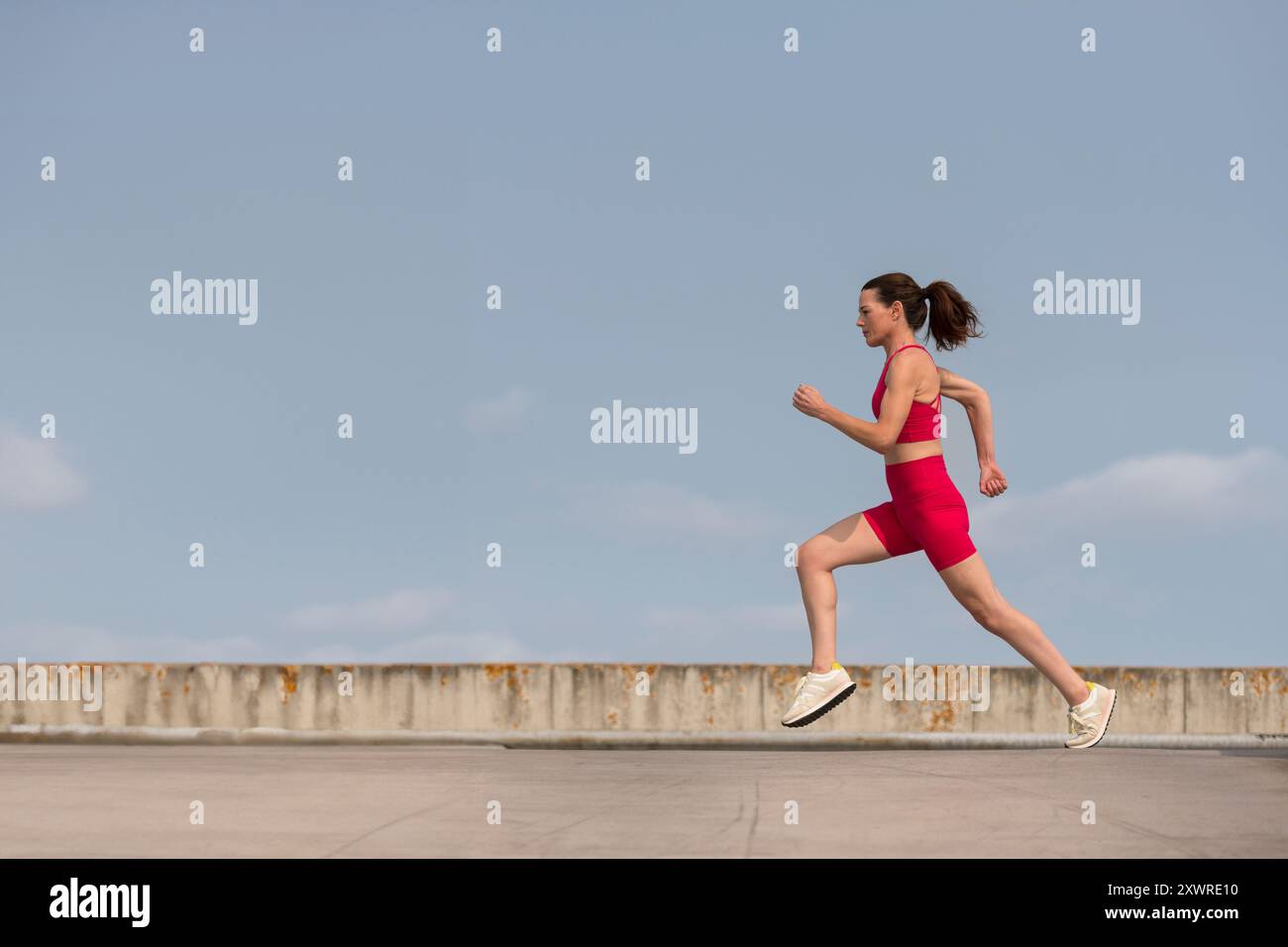 Sporty woman runner wearing red sports clothing, outdoor urban fitness ...