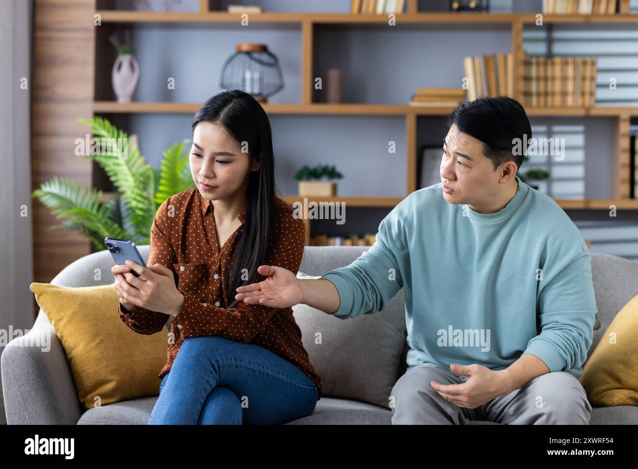 Asian family mature couple sitting on couch involved in conversation ...