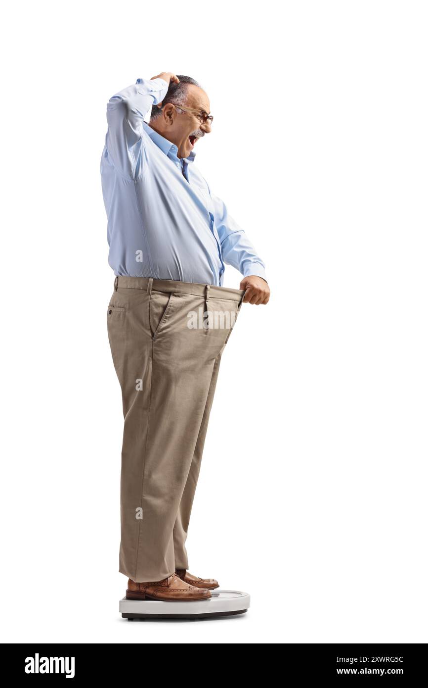 Overjoyed mature man trying on pants and standing on a scale, weight ...
