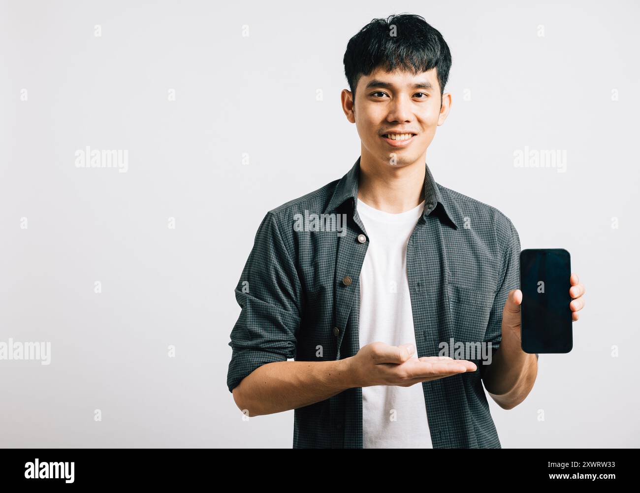 Portrait Asian smiling young man show mobile phone blank screen and ...