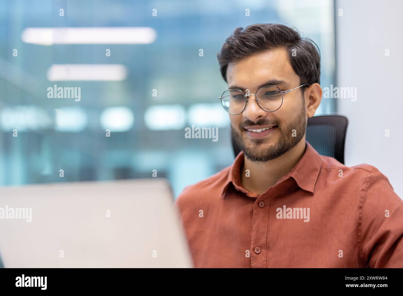 Smiling professional man using laptop in modern office. Confident ...