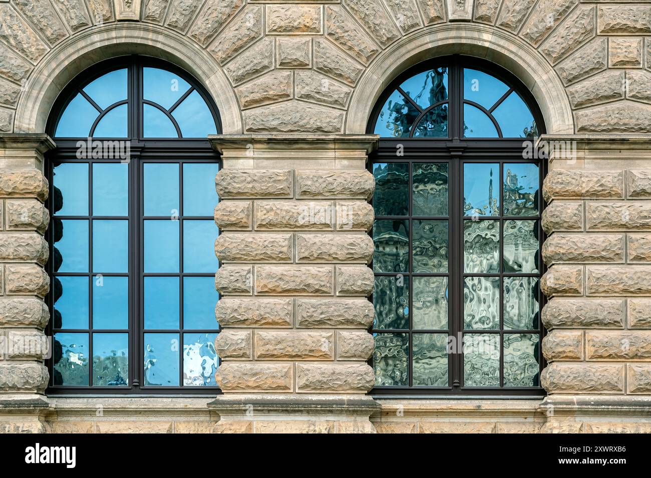 Two arched windows with a metal frame on a beige wall background. From ...
