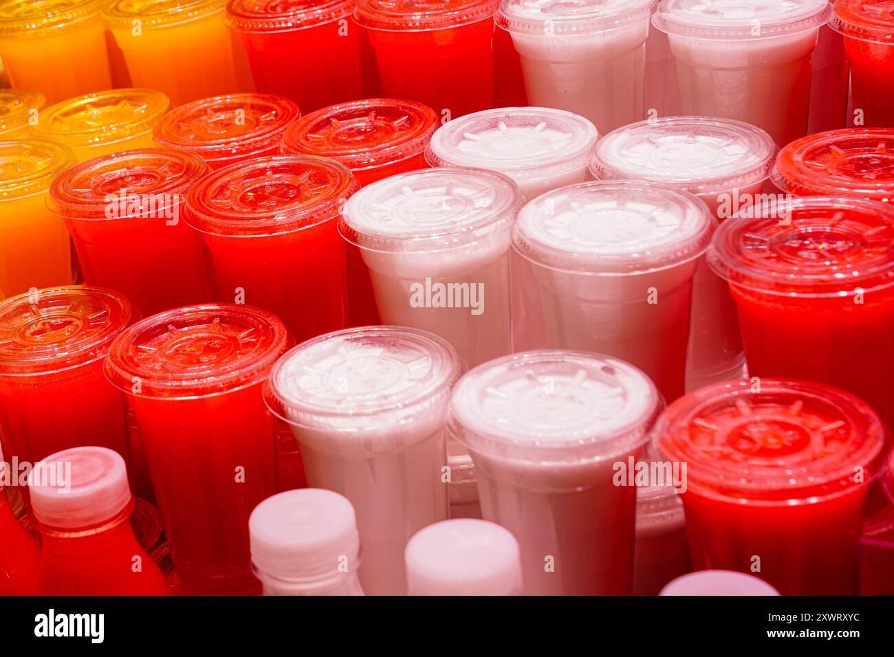 Freshly squeezed juices of various fruits in transparent plastic cups ...