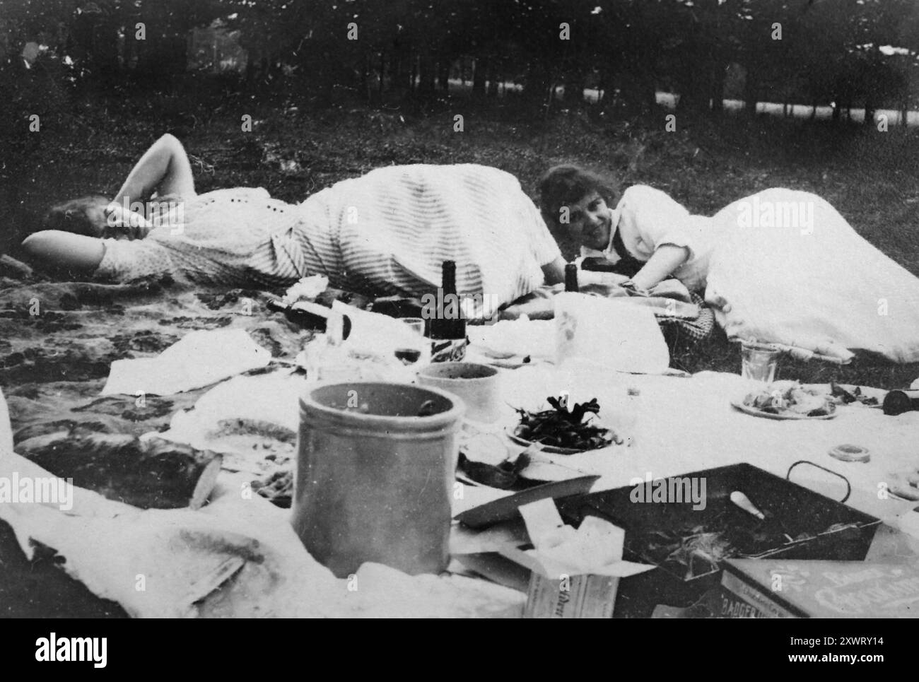 Two women are sprawled out on a blanket after helping consume a picnic ...