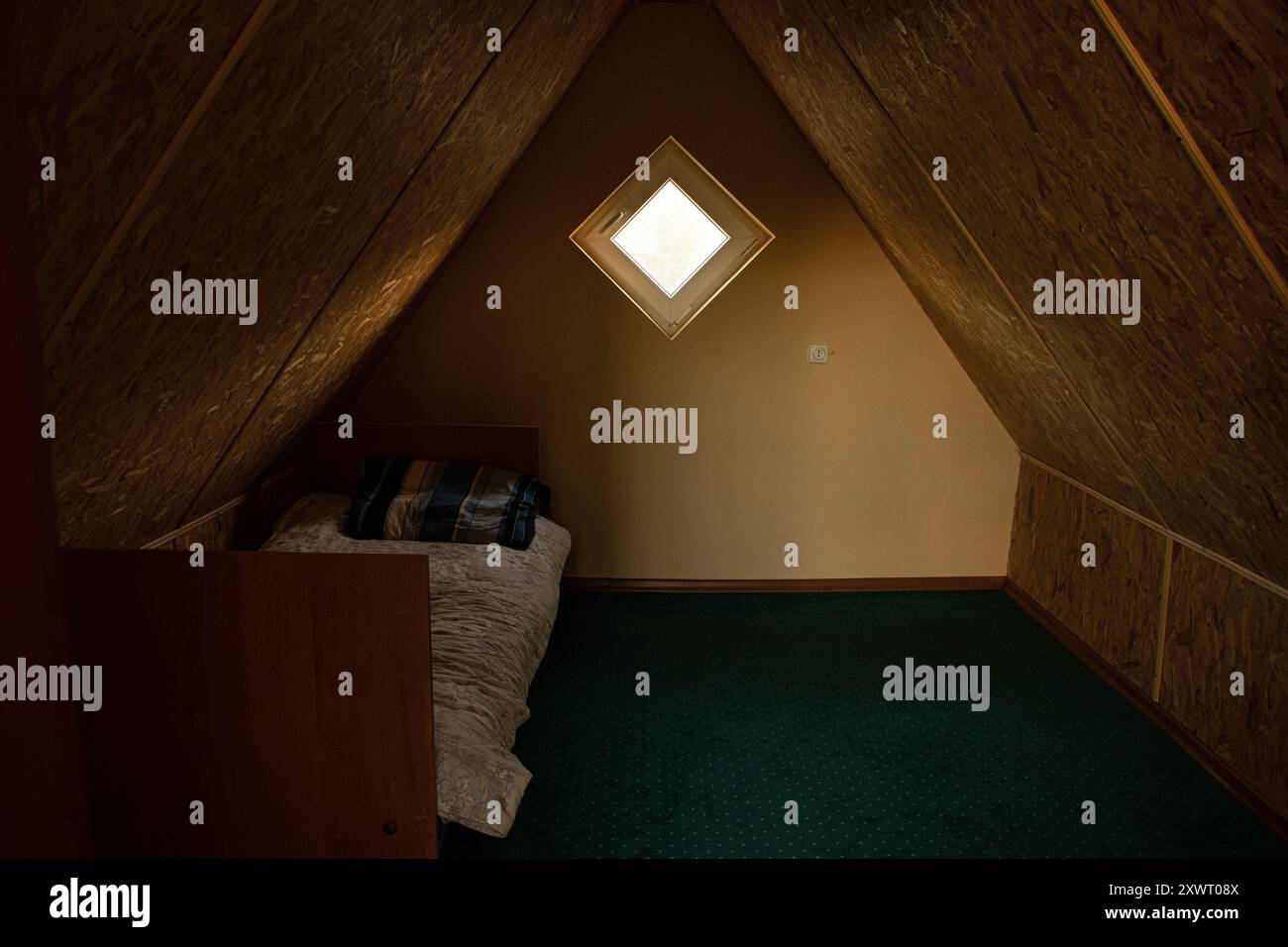 Attic bedroom with one bed and a small window in a village on a dacha ...