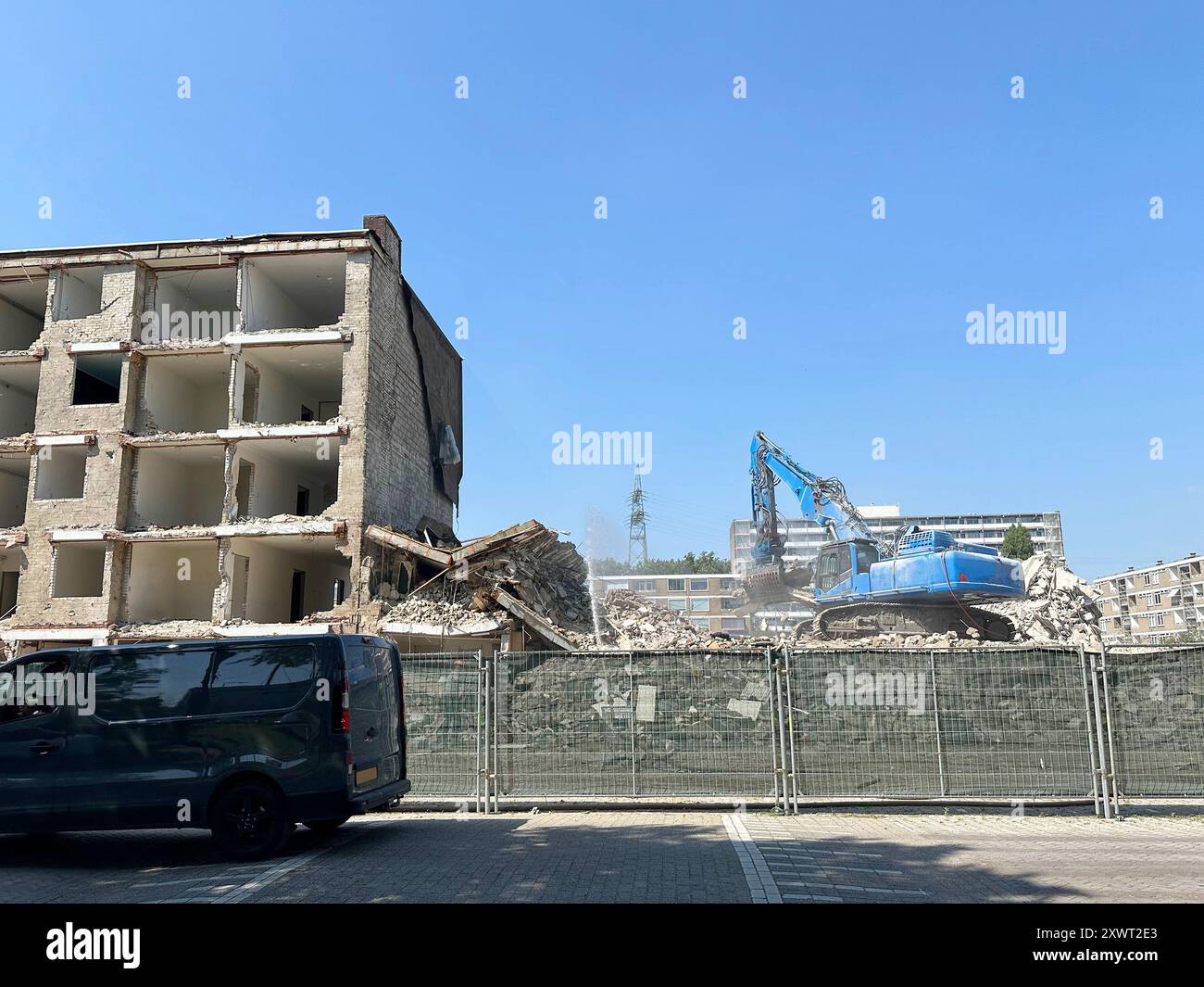 Demolition of building with excavator under blue sky Stock Photo - Alamy
