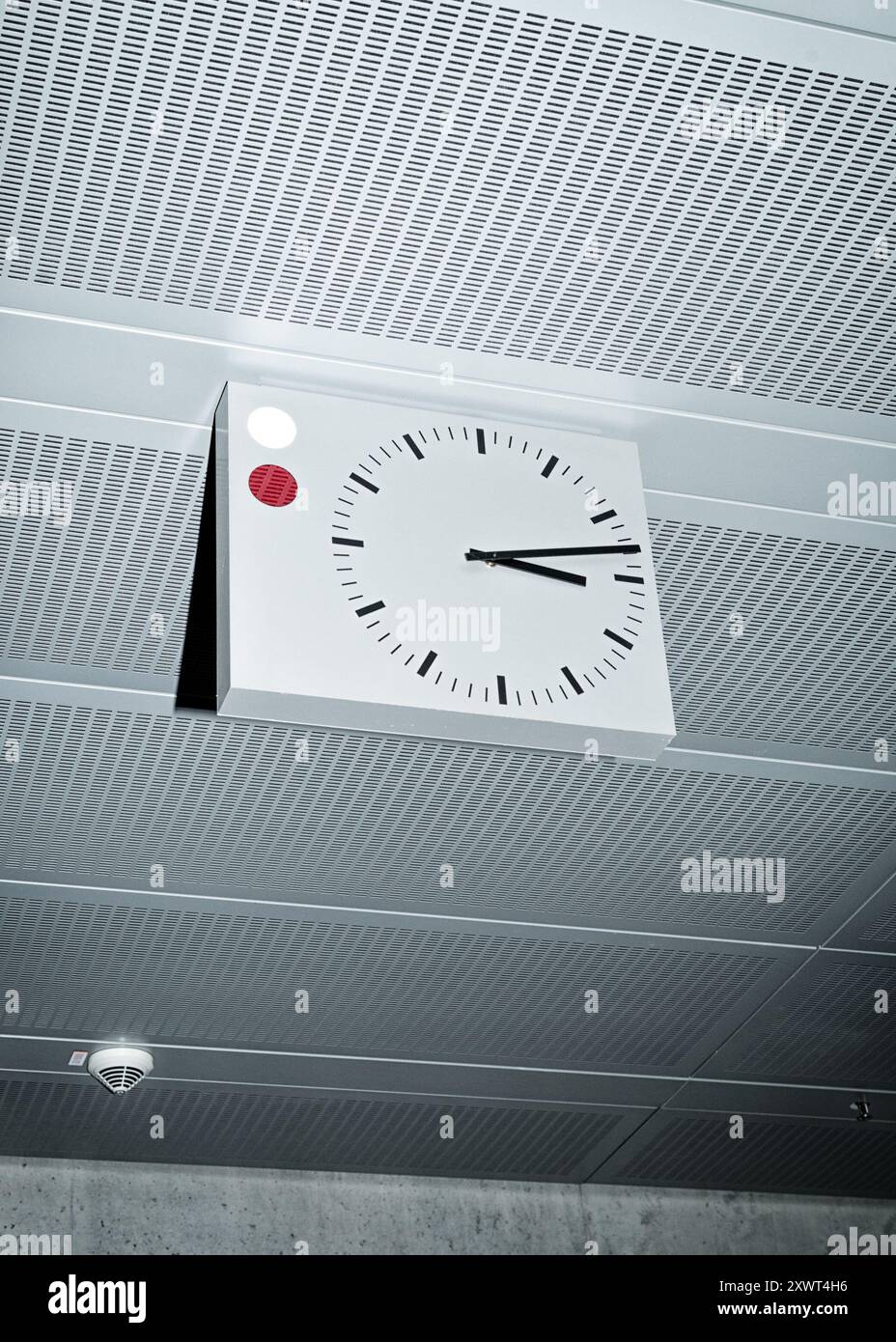 A minimalist wall clock is mounted on a contemporary, perforated ...