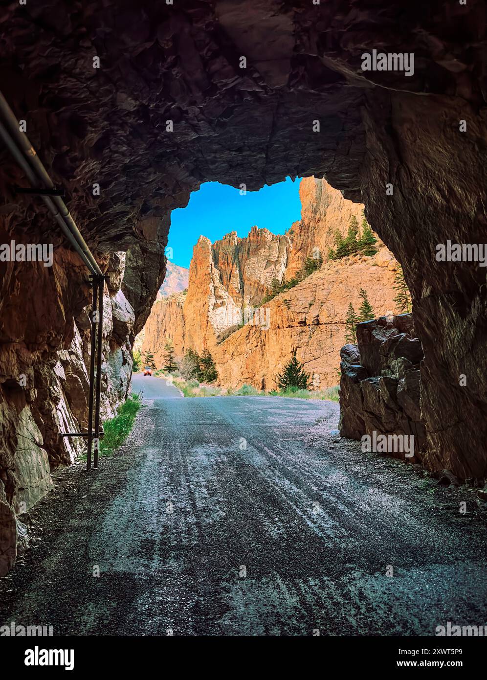 In tunnel looking out entrance you see jagged cliffs & mountains with ...