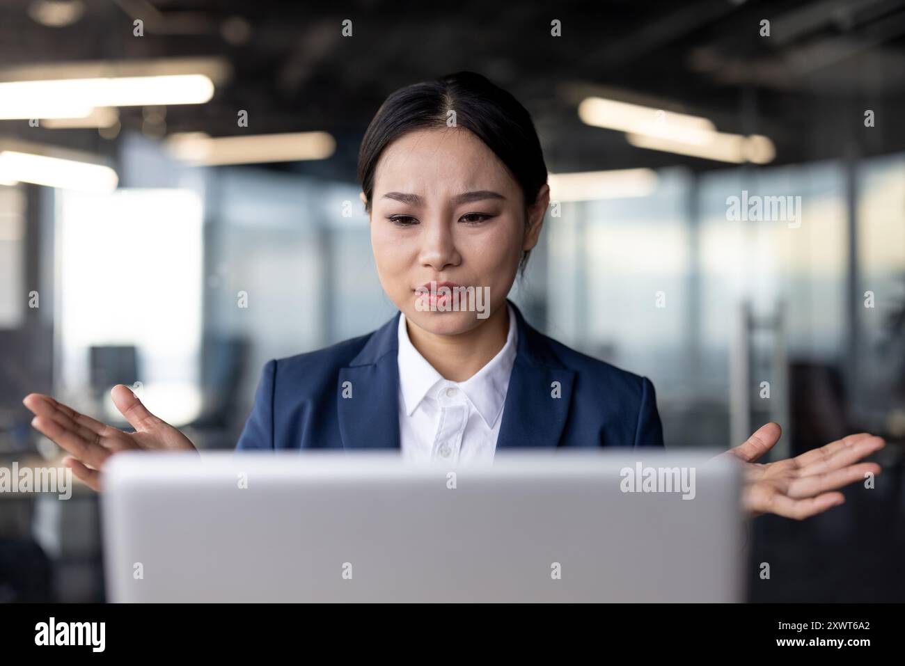 Confused Asian businesswoman with laptop in office expressing ...