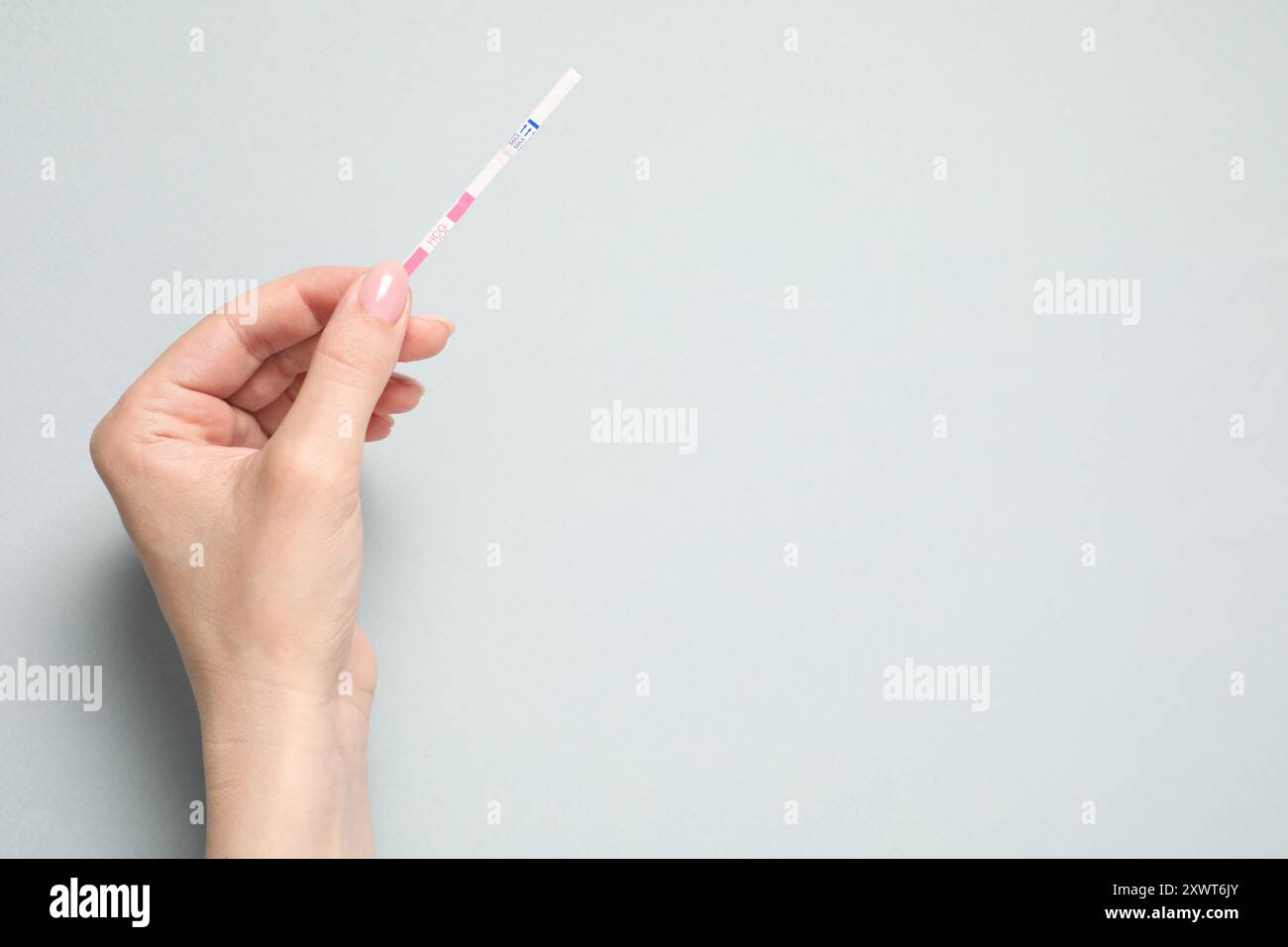Woman holding pregnancy test on light grey background, top view. Space ...