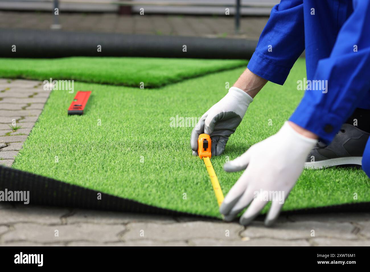Man in uniform installing artificial turf outdoors, closeup Stock Photo ...