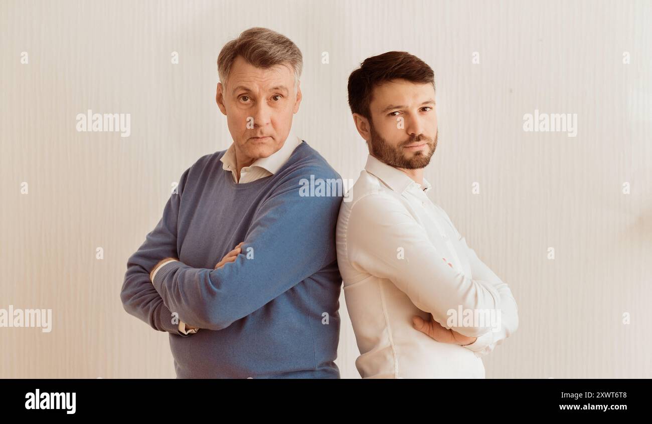 Adult Son And Senior Father Standing Crossing Hands Indoor Stock Photo ...