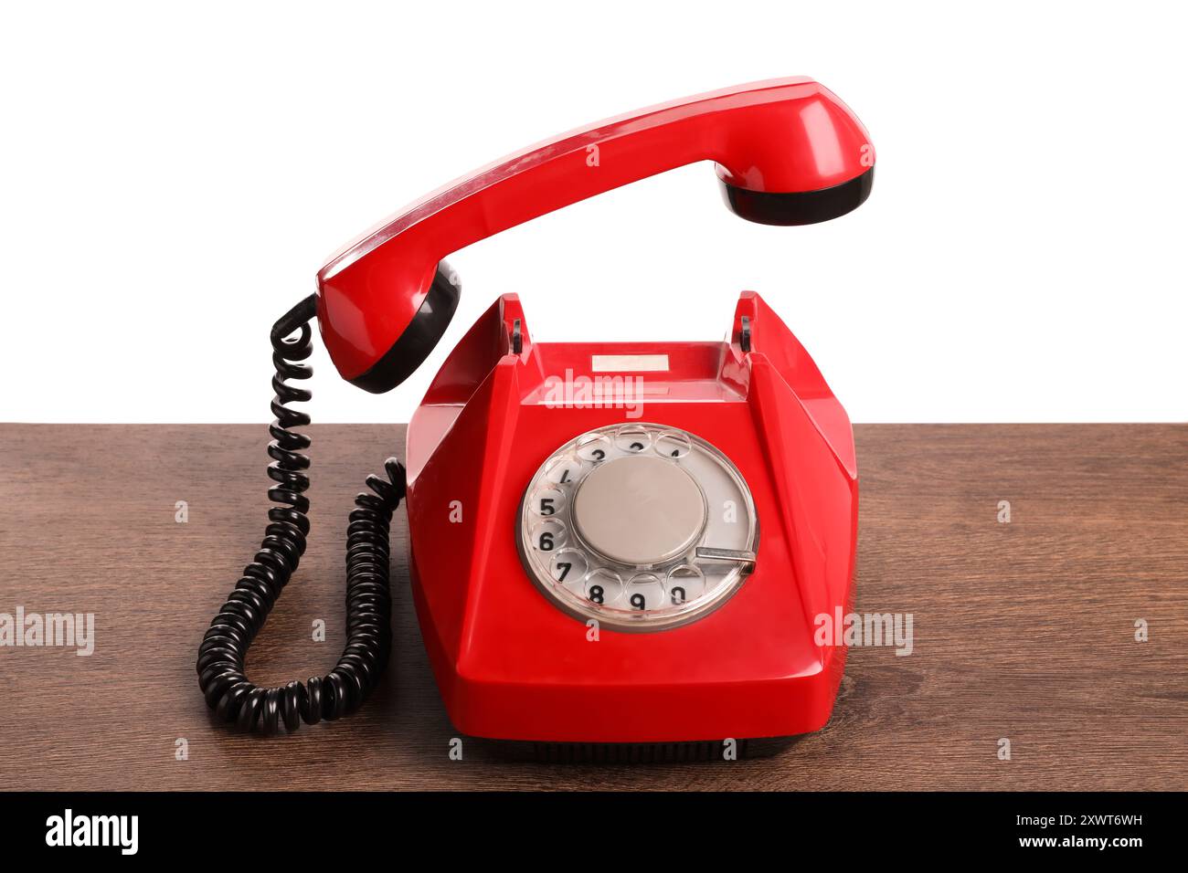 One red telephone with handset on wooden table against white background ...