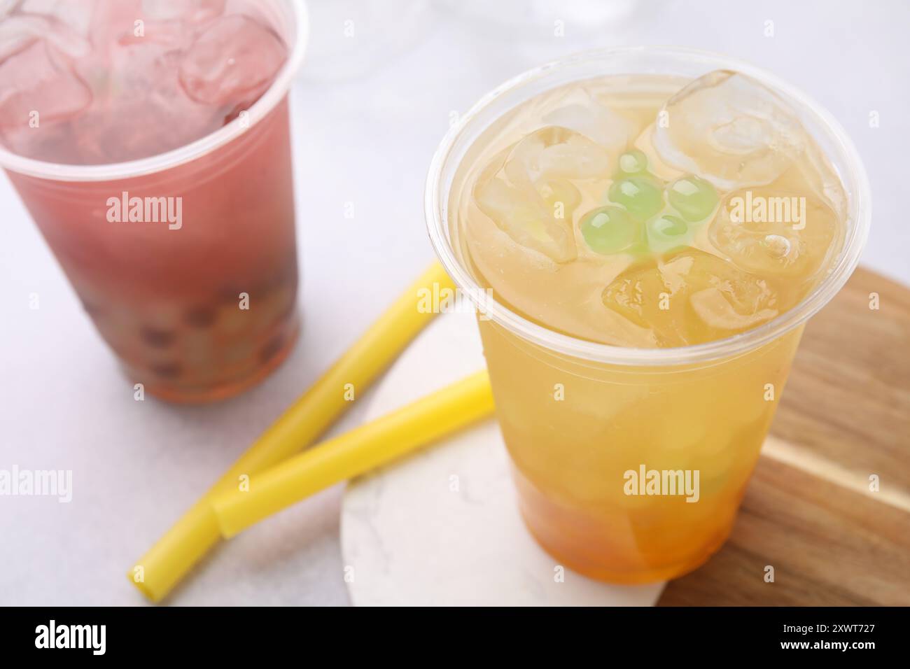 Tasty bubble tea in plastic cups and straws on light table, closeup ...