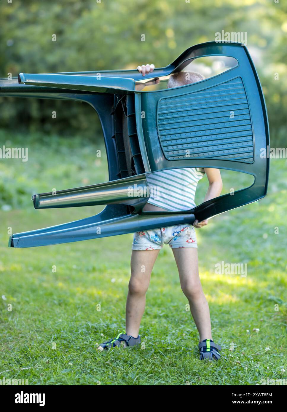 A little boy carries a plastic chair in the garden Stock Photo - Alamy