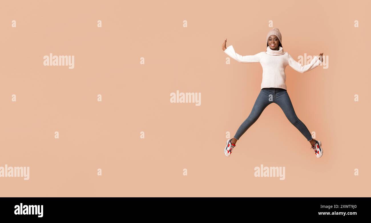 Emotional black woman in winter hat jumping up Stock Photo - Alamy