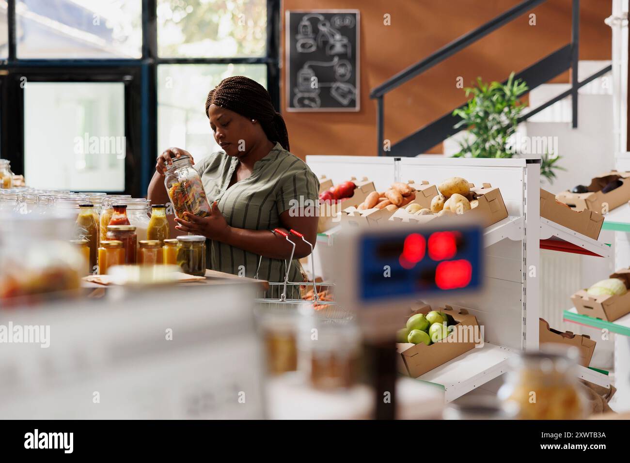 African American woman holding a glass jar, shopping for fresh organic ...