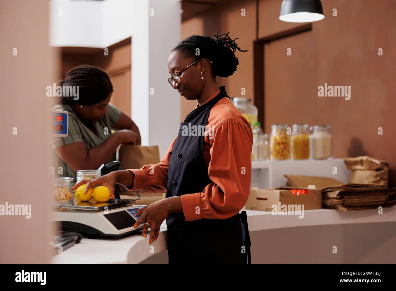 An aproned African American woman assists a customer at a fresh food ...