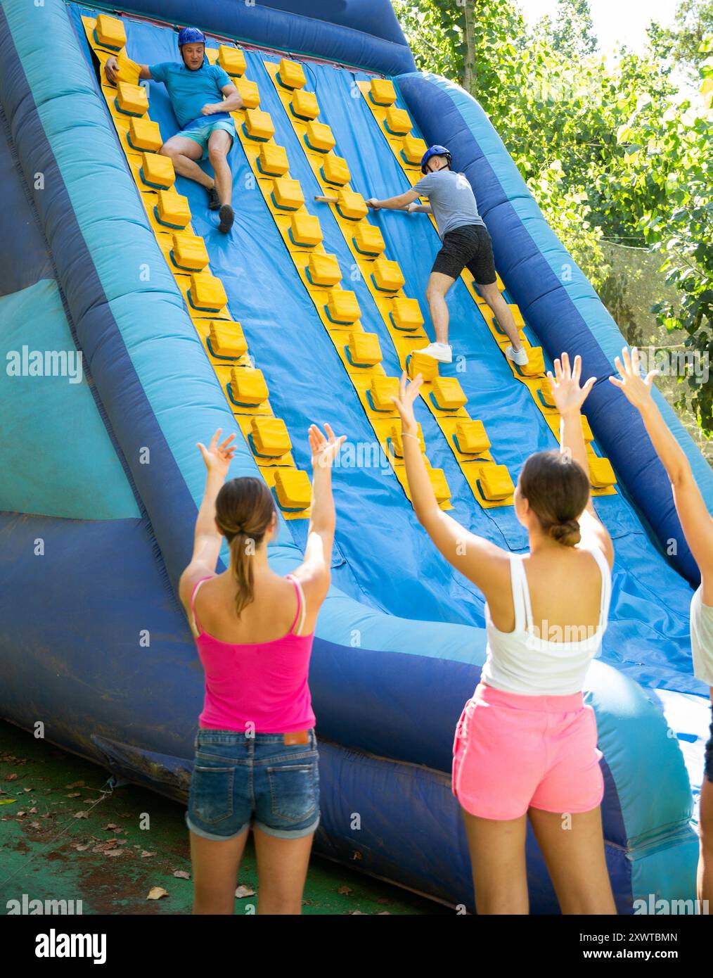 Father and son trying to climb on top of slide in amusement park Stock ...