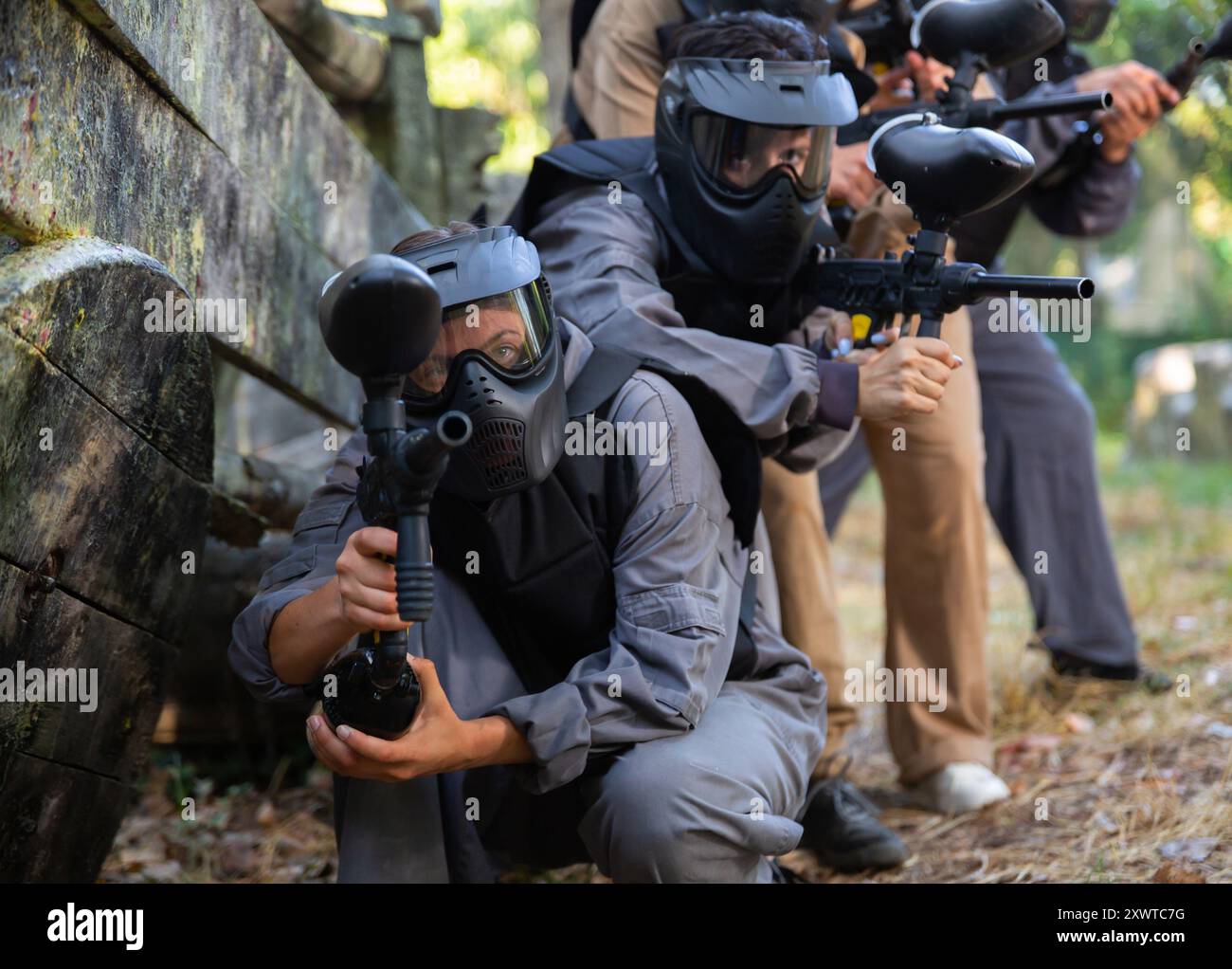 Group of paintball players aiming and shooting with guns outdoors Stock ...