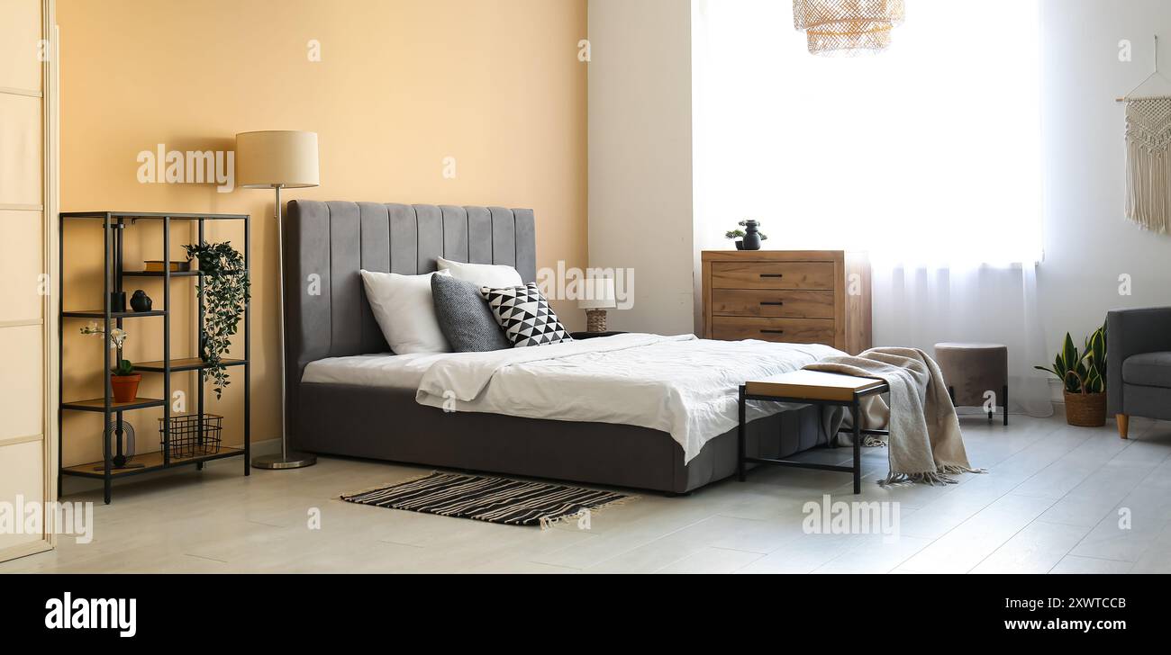 Cozy bed, chest of drawers and bedside bench in beautiful bedroom Stock ...