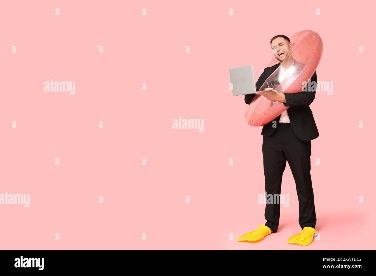 Happy office worker in flippers with laptop and inflatable ring on pink ...