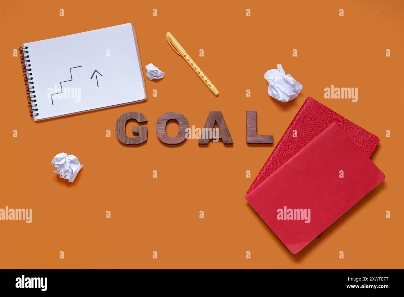 Notebooks, crumpled paper and letters spelling word GOAL on orange ...