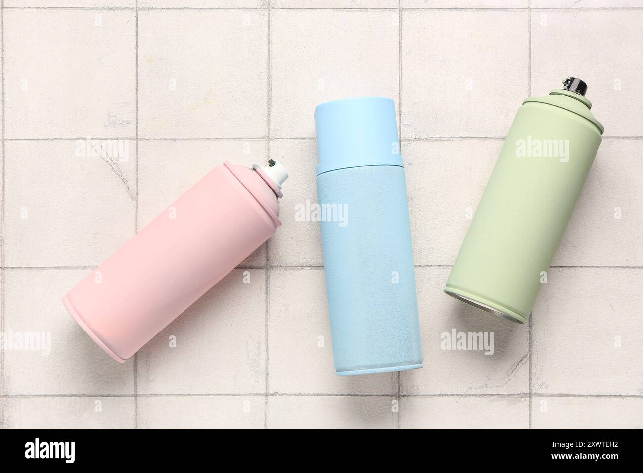 Different spray paint cans on tile background Stock Photo - Alamy