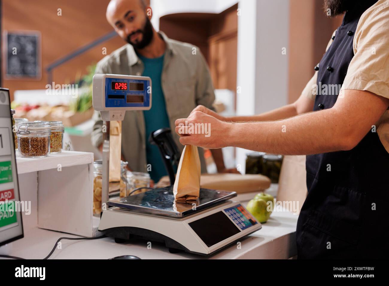 At checkout counter caucasian vendor places brown paper bag on weighing ...