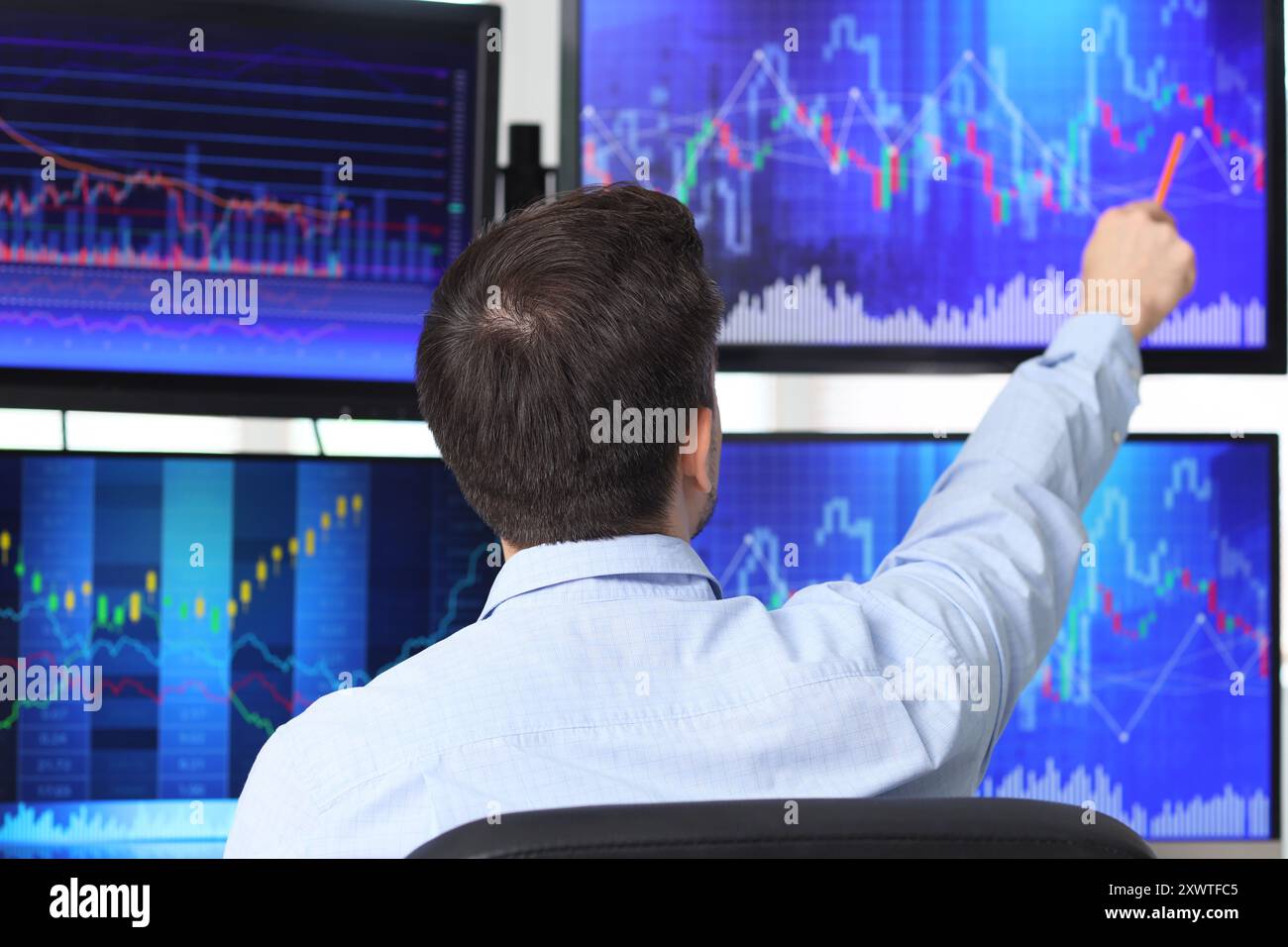 Male trader working at table in office, back view Stock Photo - Alamy