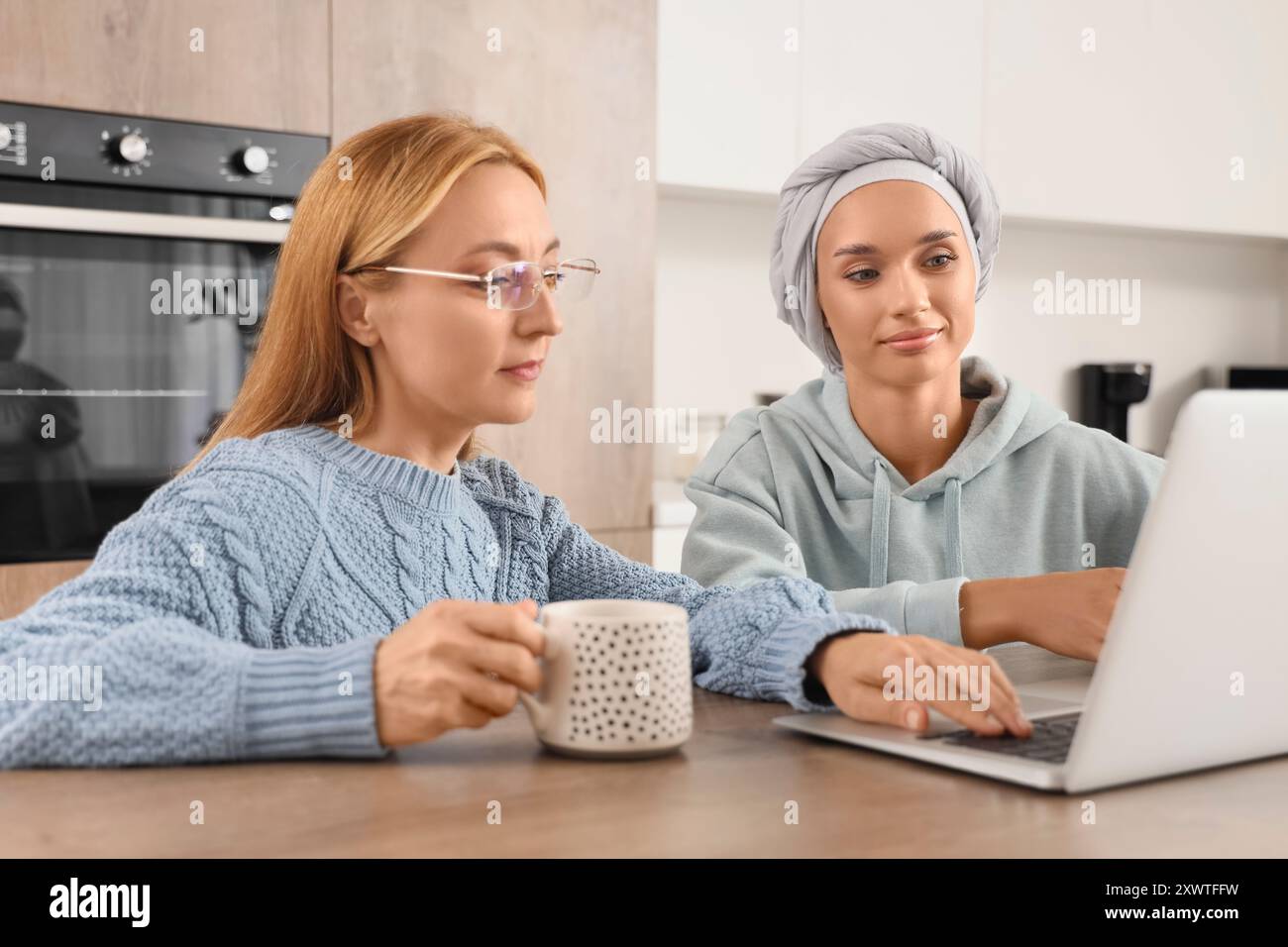 Young woman after chemotherapy using laptop with her mother in kitchen Stock Photo - Alamy