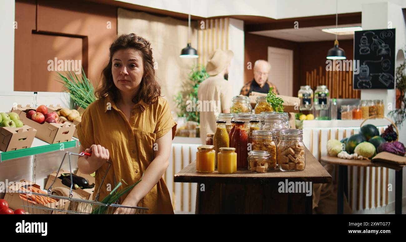Vegan woman buying organic pantry staples from zero waste supermarket ...