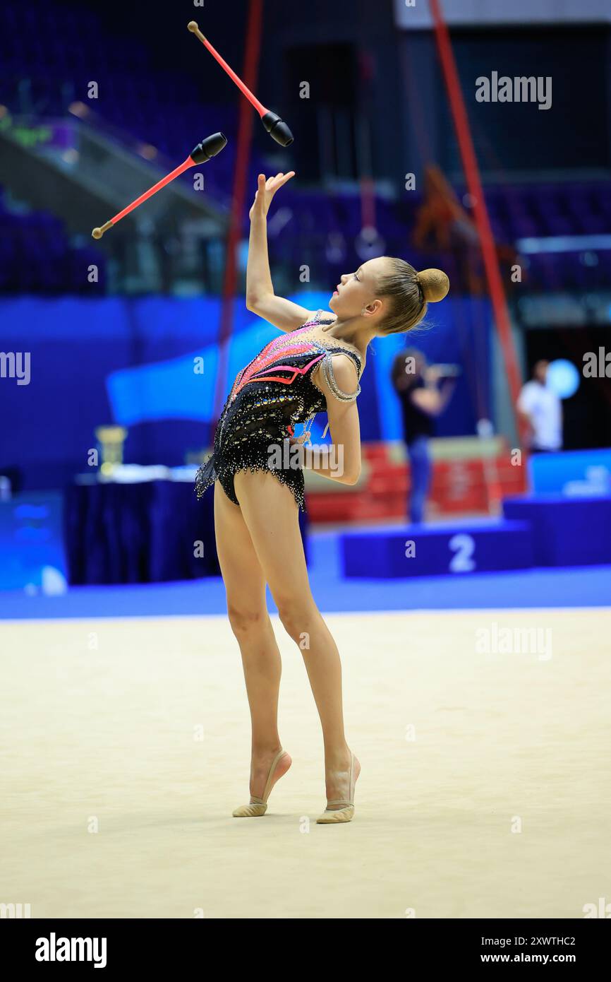 A gymnast with clubs shows talent, flexibility, and grace at a rhythmic ...