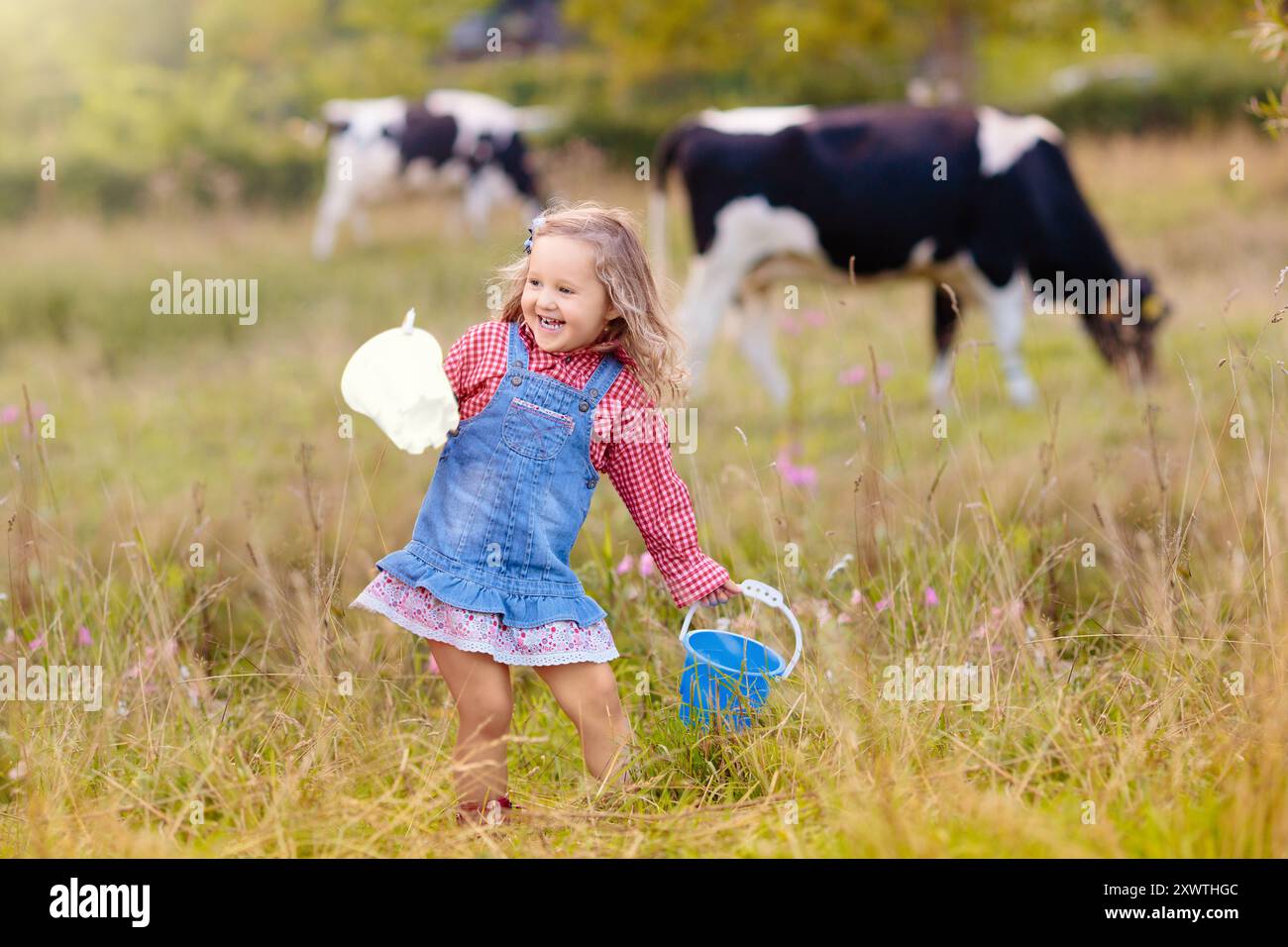 Kids watch cow on dairy farm. Children with milk bucket on country ...