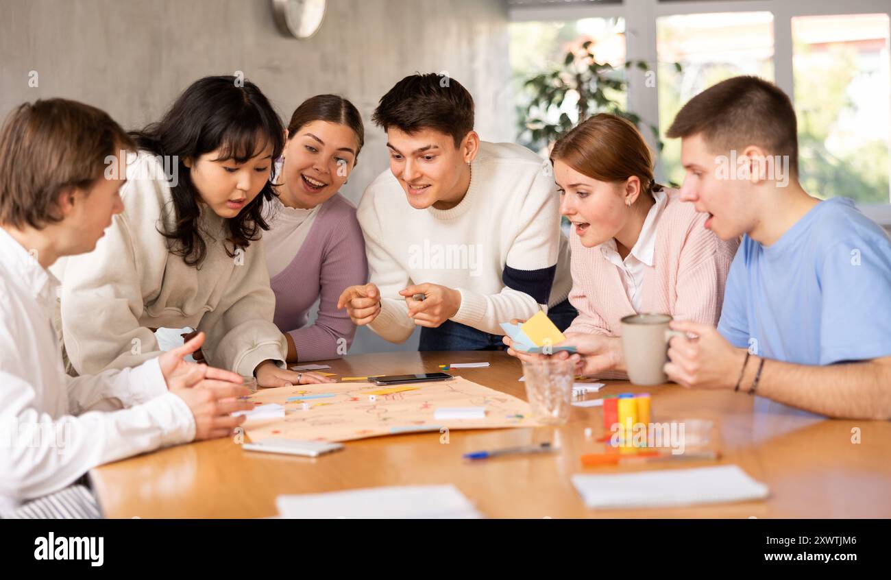 Happy students playing board game at table in campus Stock Photo - Alamy
