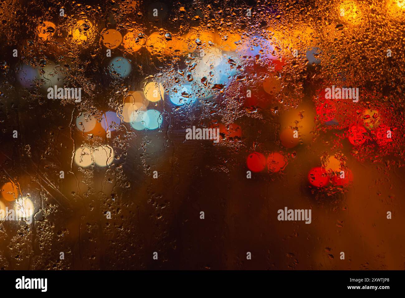 Blurred rainy night window with colorful bokeh lights reflecting from ...