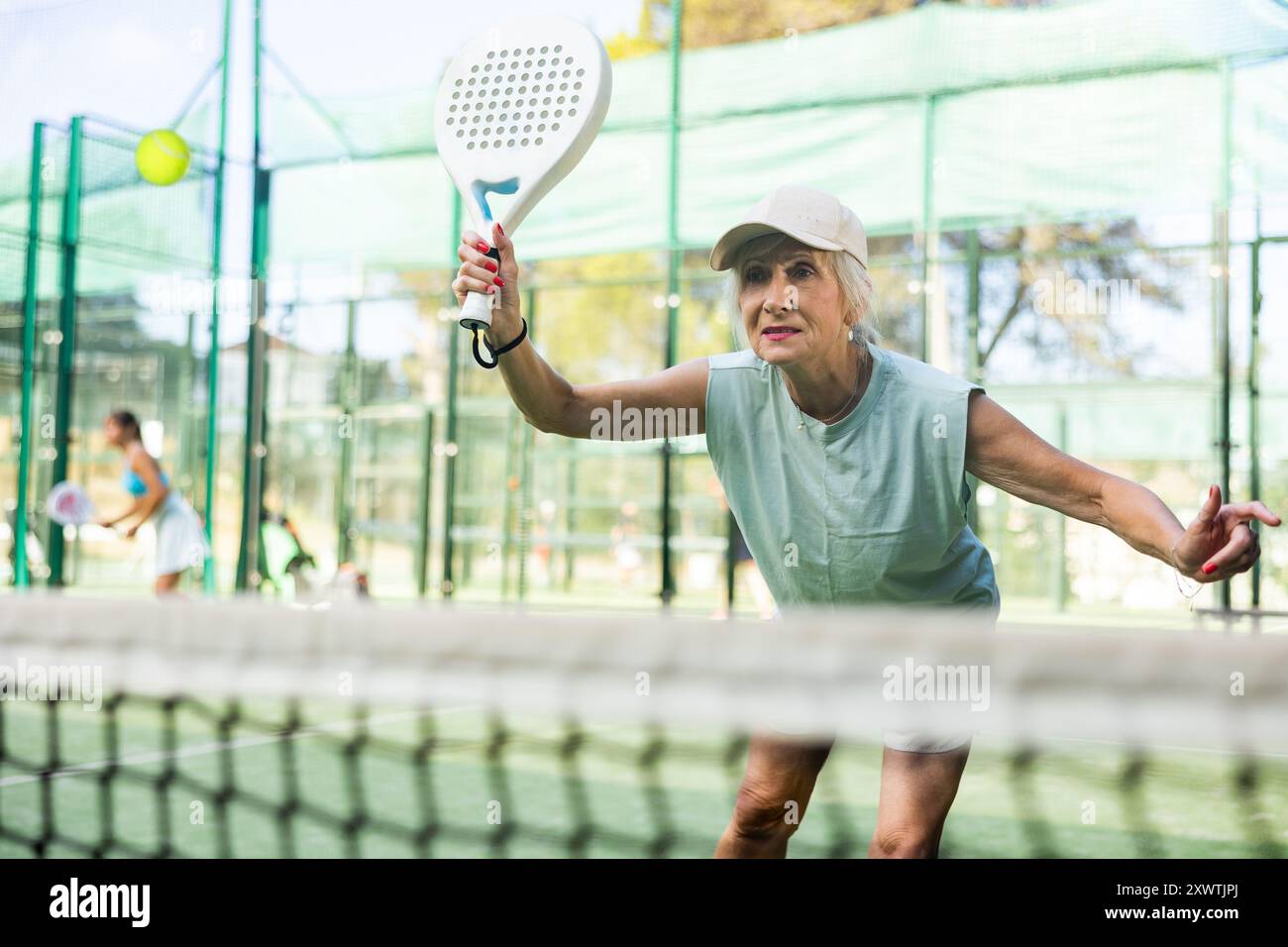 Senior woman playing padel tennis match during training on court Stock ...